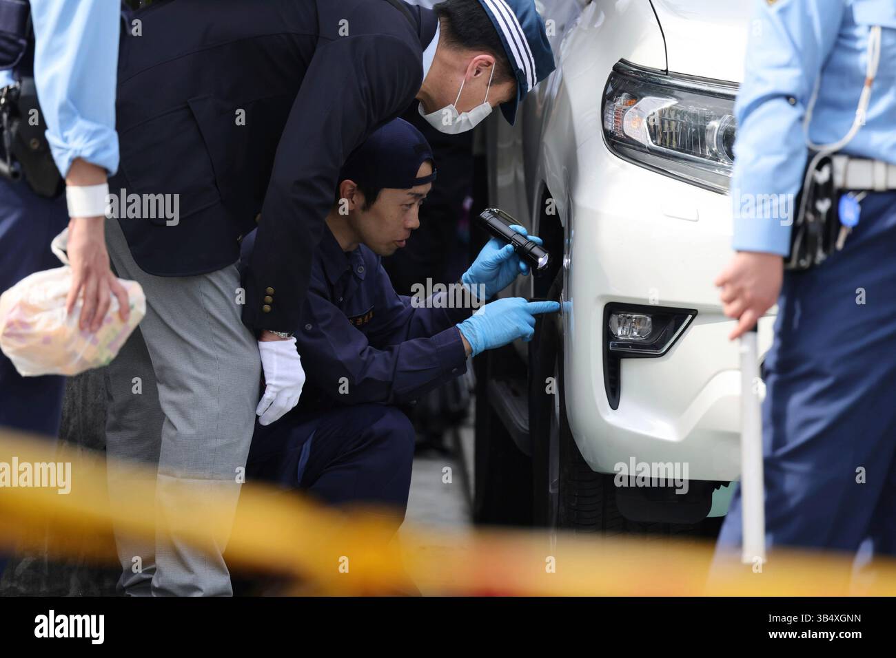 Osaka Prefectural police detectives investigate a car left at a crime ...