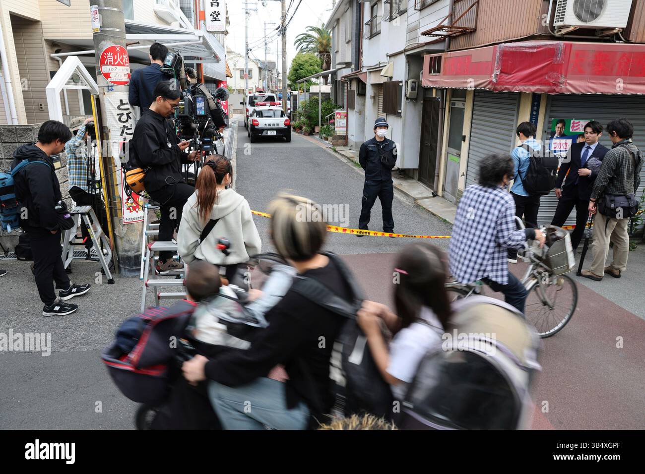 Osaka Prefectural police officers control traffiic around a crime site ...