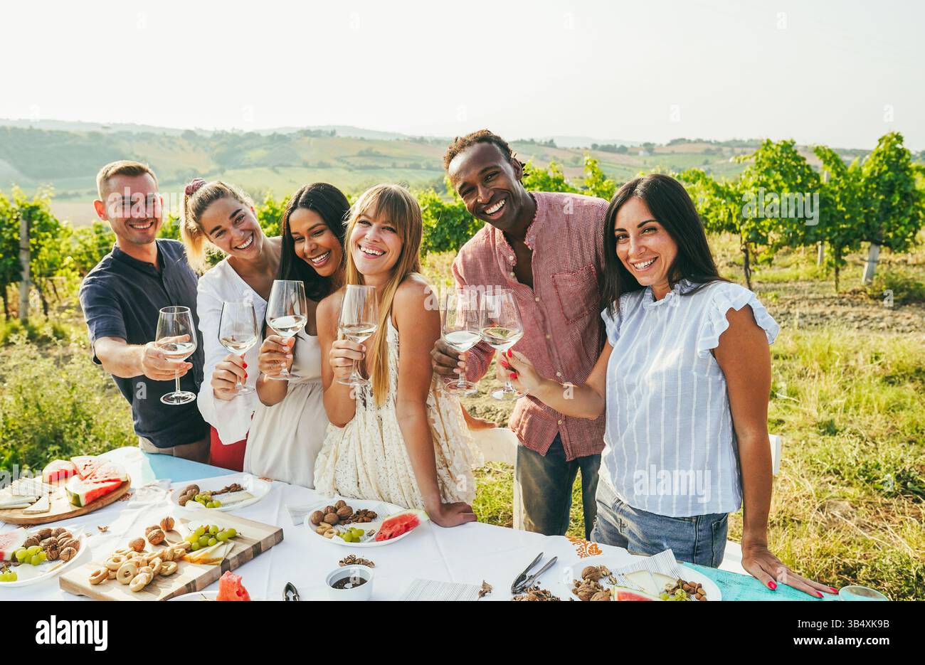 Happy friends having fun drinking white wine and eating together ...