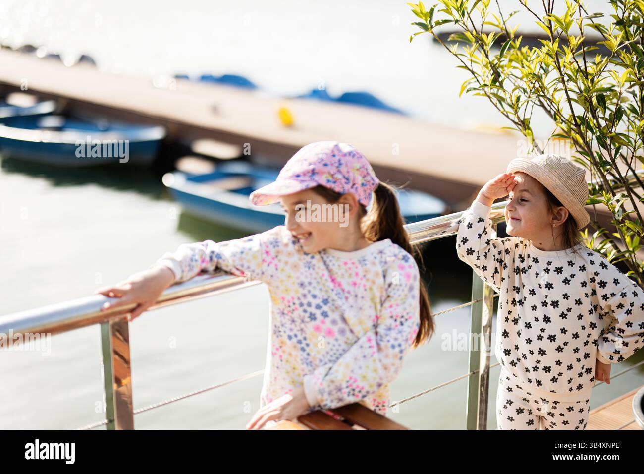 Two smiling children wearing hats enjoying their time on a riverside ...