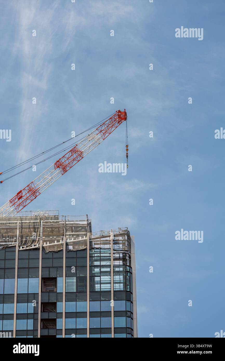 Tower crane stretches above glass paneled modern skyscraper ...