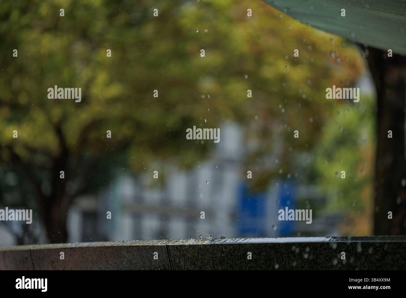 Water droplets captured in still motion fall onto fountain ledge ...