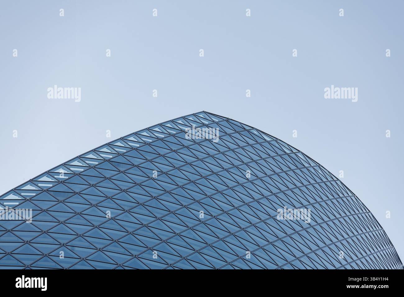 Modern architectural structure features sleek, curved surface with triangular glass panel grid ...