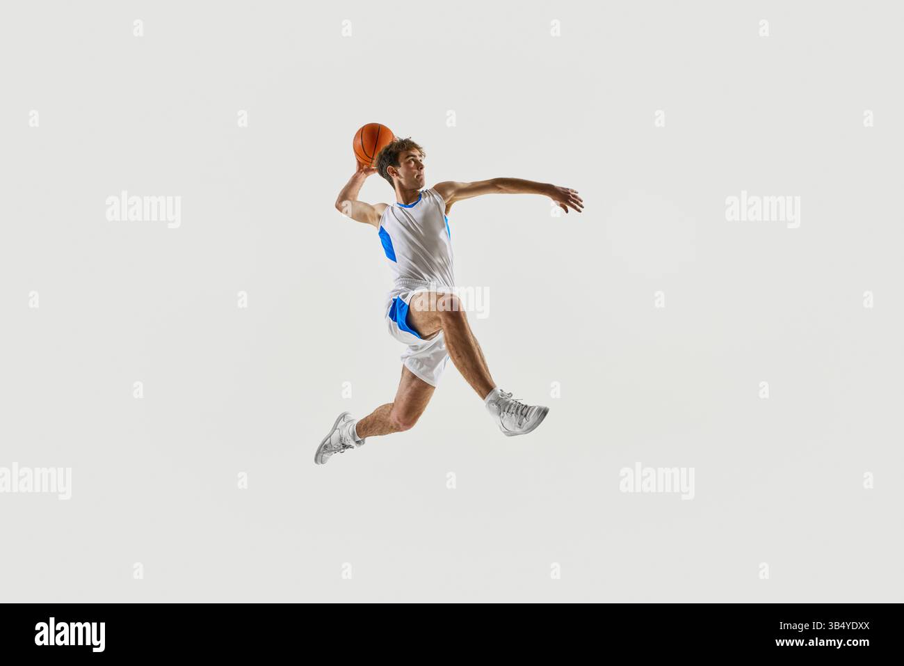 Dynamic photo. Young basketball player mid-jump, leaning forward with ...