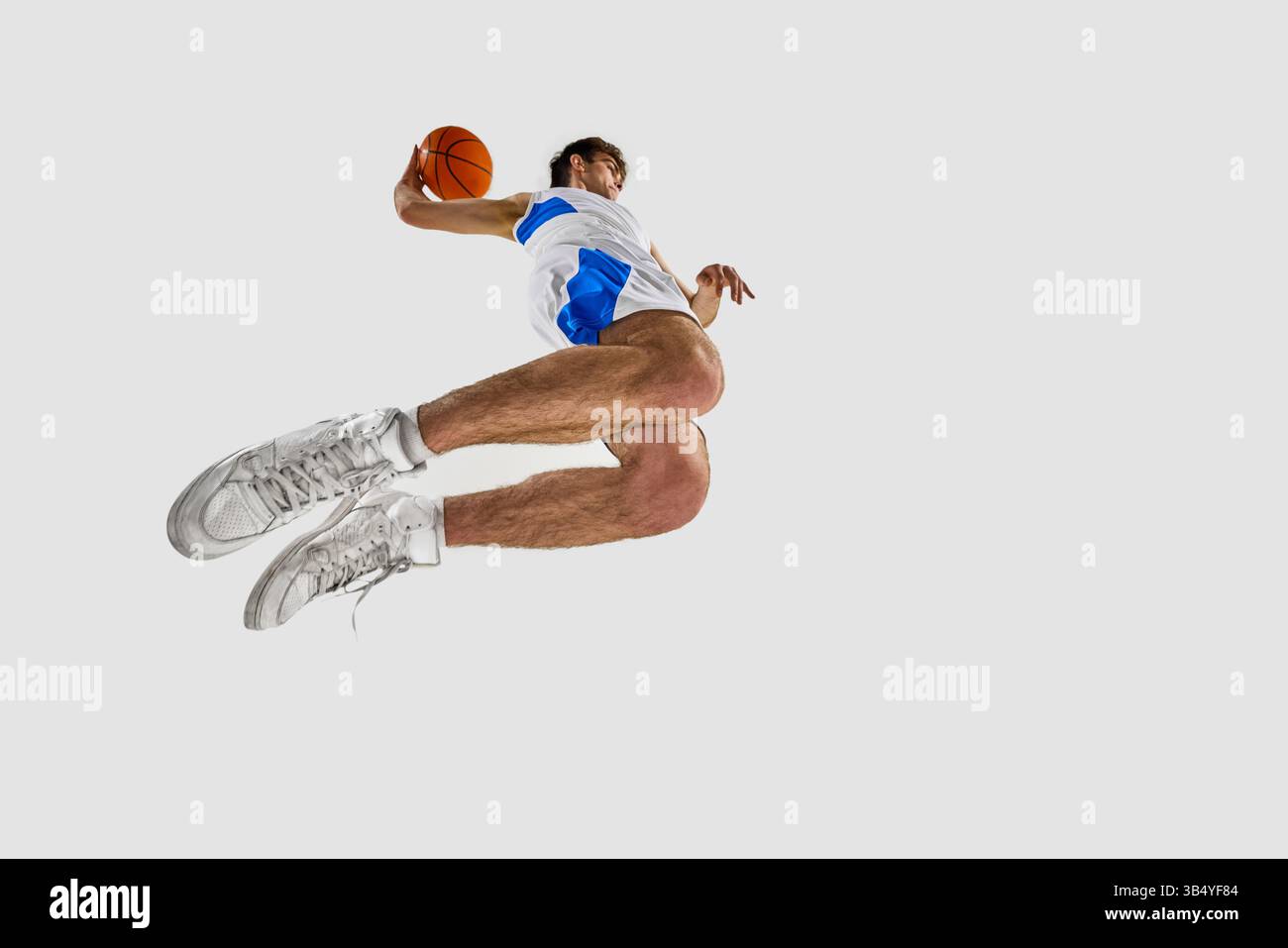 Low angle view of young basketball athlete in mid-air, fully extended ...