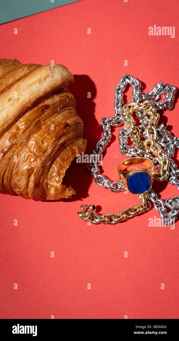 Luxury & Everyday Contrast – Croissant, Chain & Ring on Red Surface ...