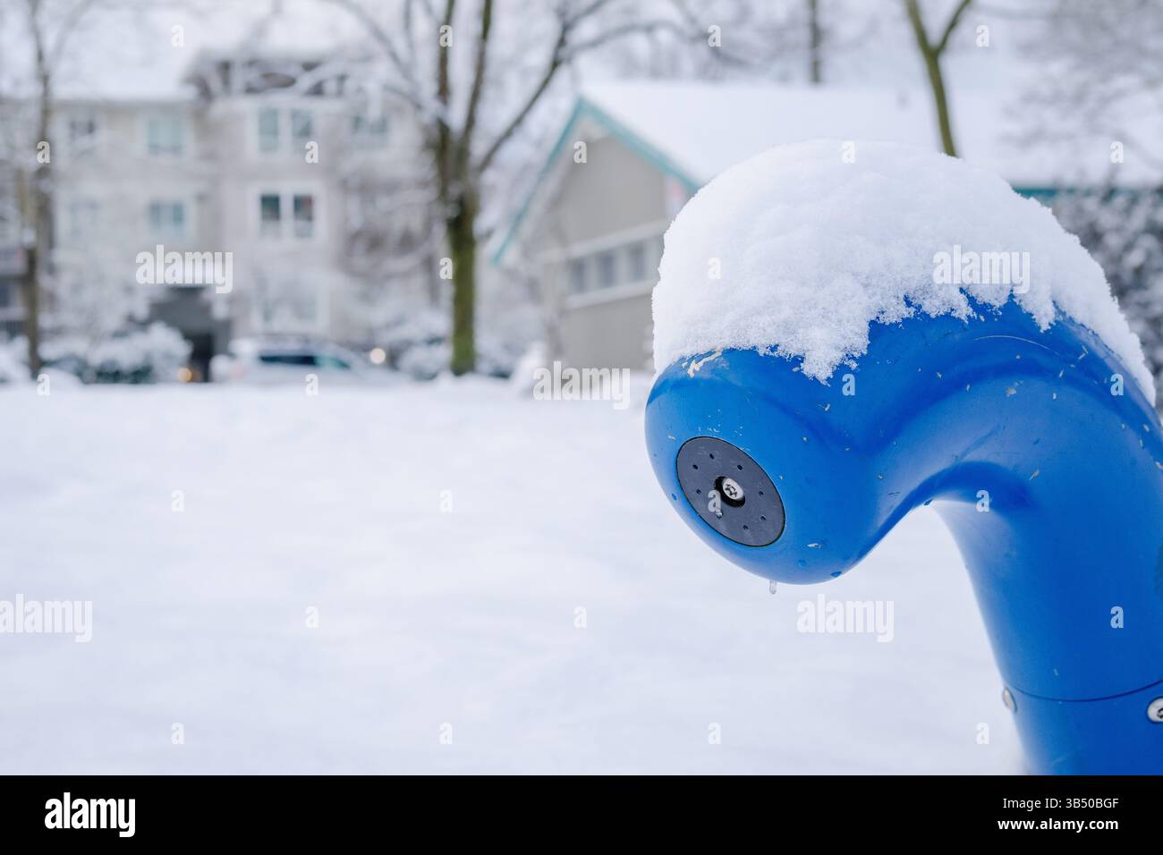Blue Kids water sprinkler or spray park nozzle covered with snow. Close up. Winterizing outdoor ...