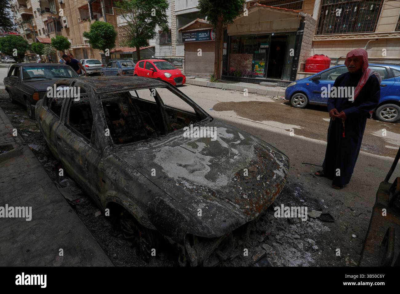 A man checks a charred car that was burnt after clashes erupted between ...
