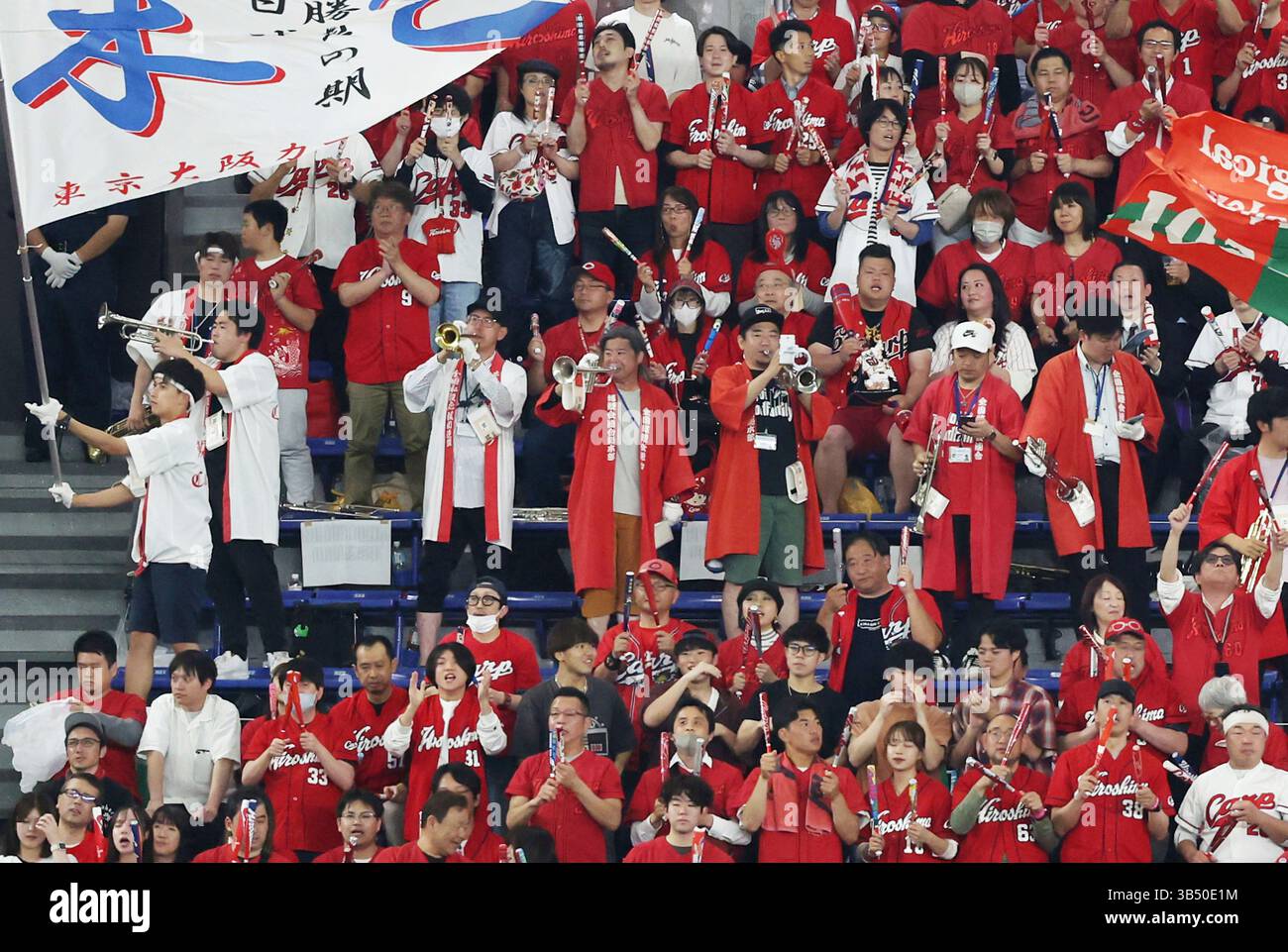 Several supporters clad in red play the trumpets to cheer the Hiroshima ...