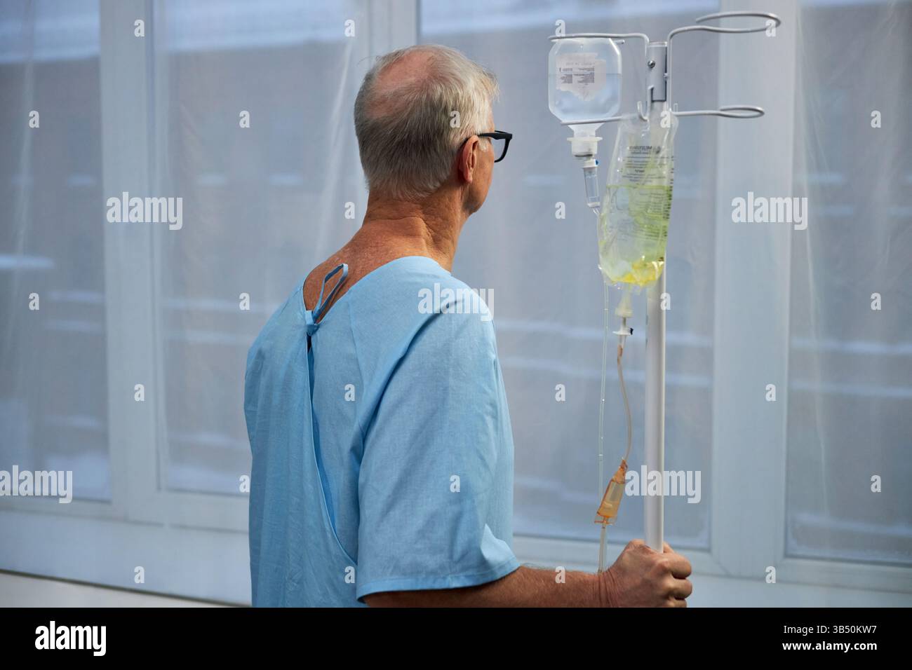Elderly Man Holding IV Drip and Wearing Hospital Gown Stock Photo - Alamy