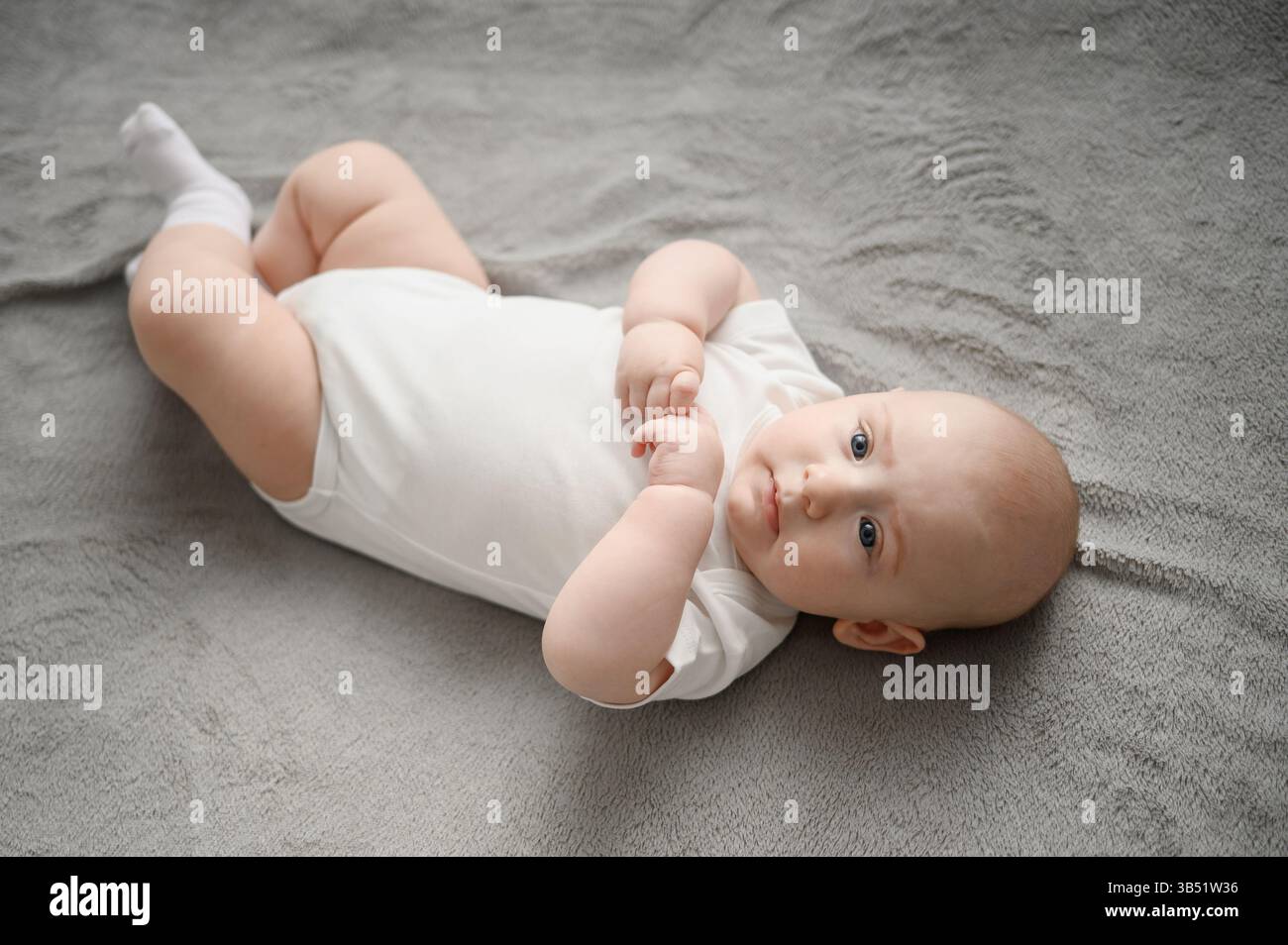 Newborn baby lies in crib, moves its arms and legs, and looks up at its ...