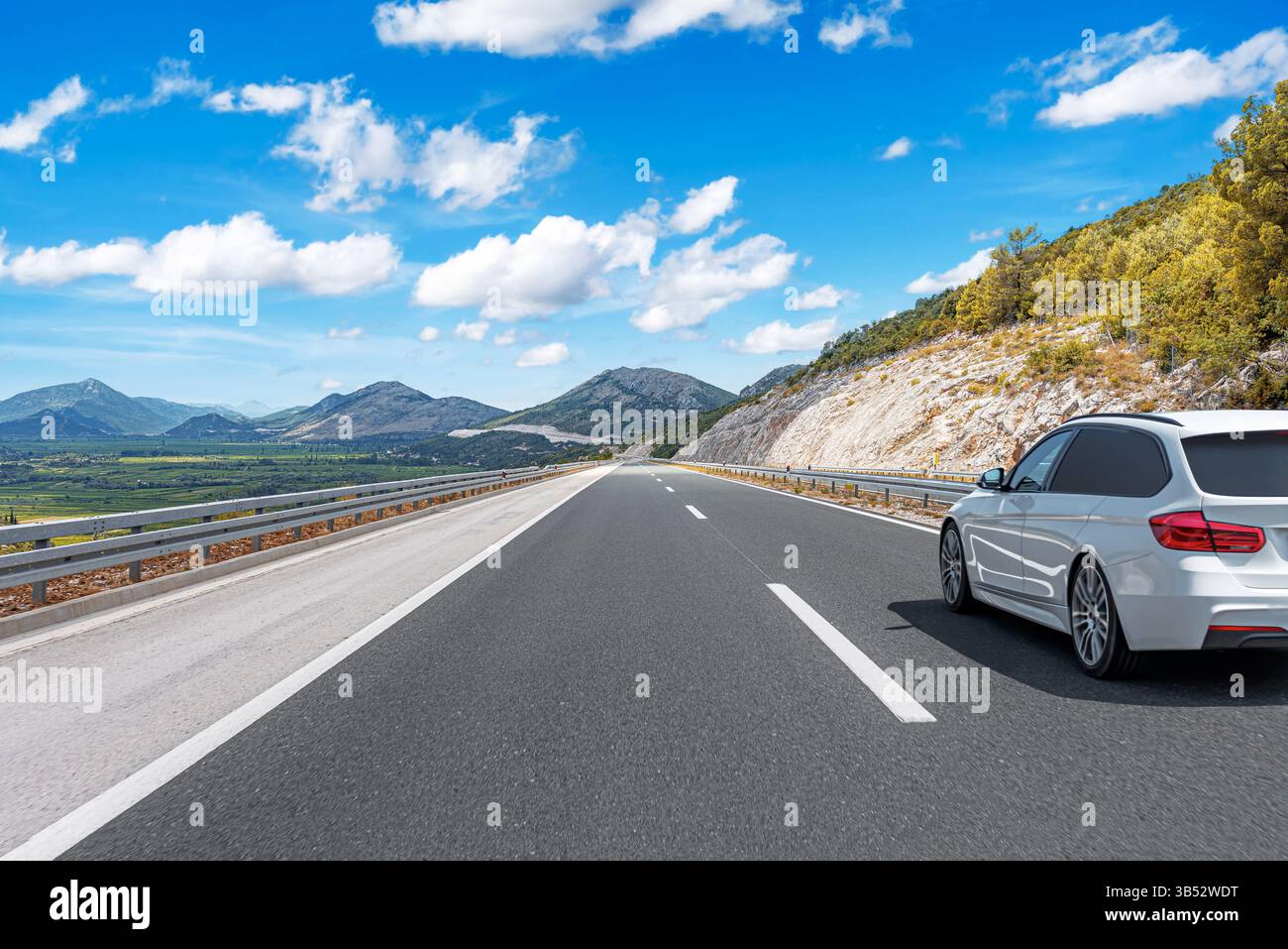 A sleek white car drives along a wide Stock Photo - Alamy