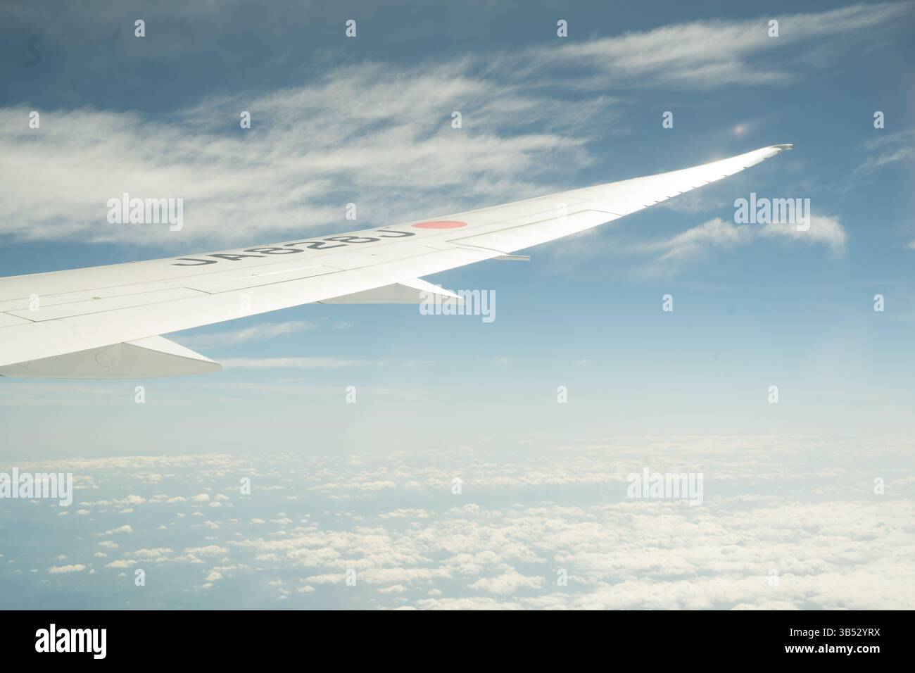 Bright view of airplane wing and clouds from passenger seat during ...