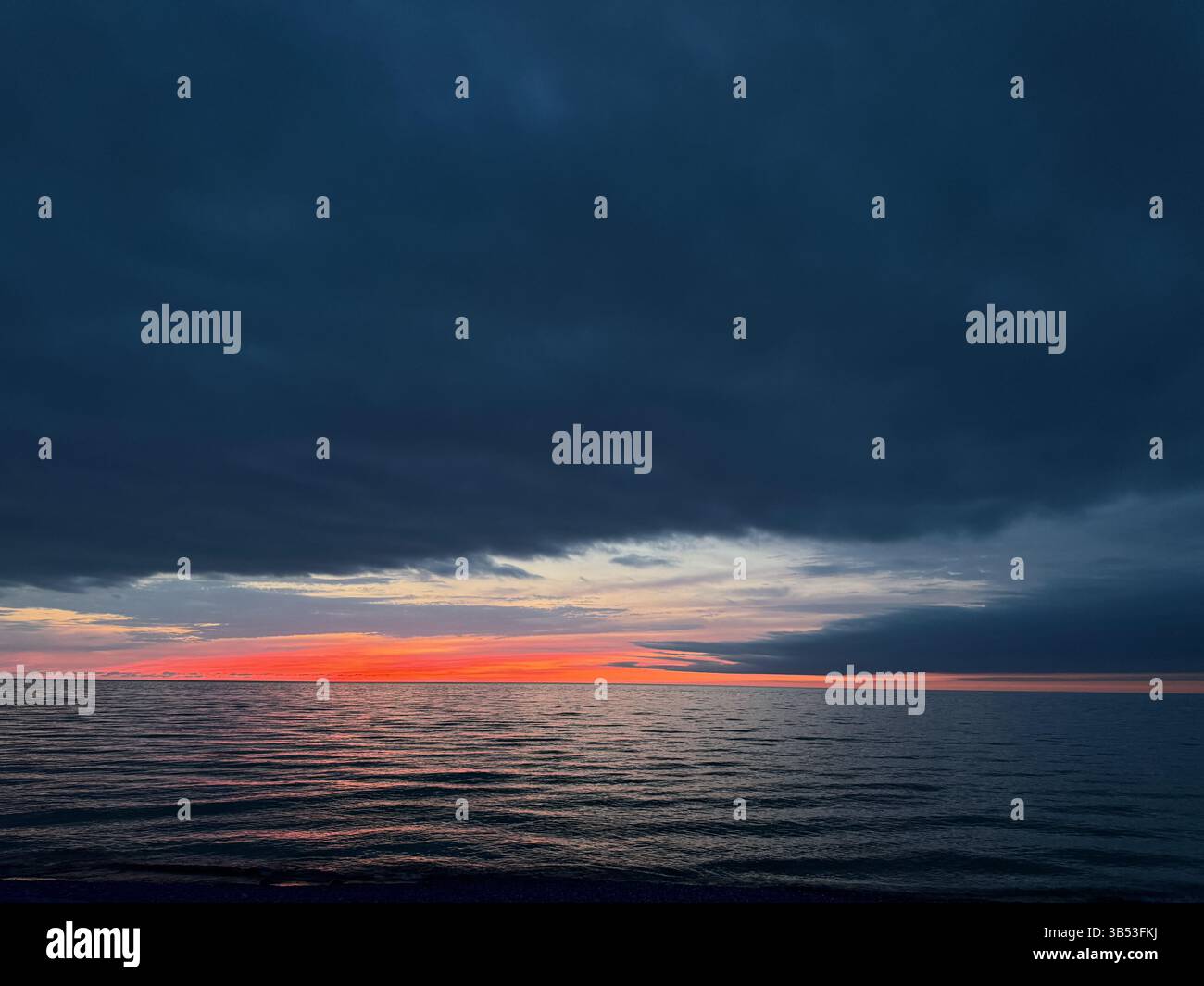This photo shows a dark, cloud-covered sky above a calm sea during ...