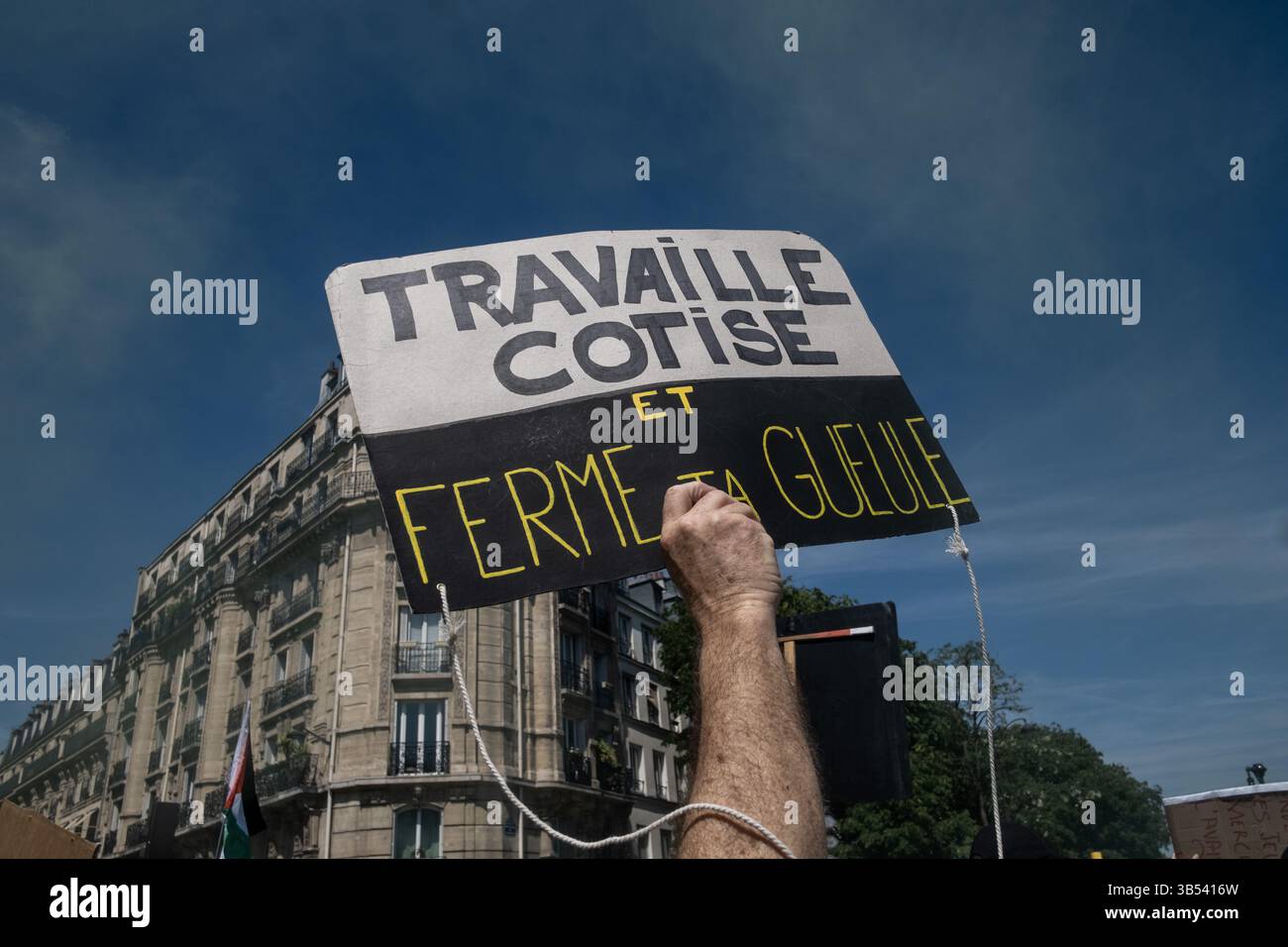 A person holds up a sign that reads, "Work, contribute, and shut up." A ...