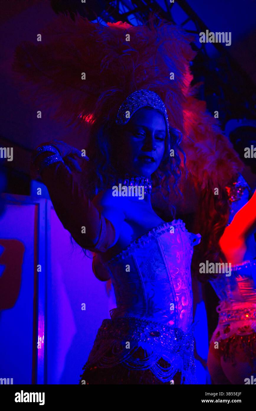 A woman in a white corset and large feathered headdress is center frame ...