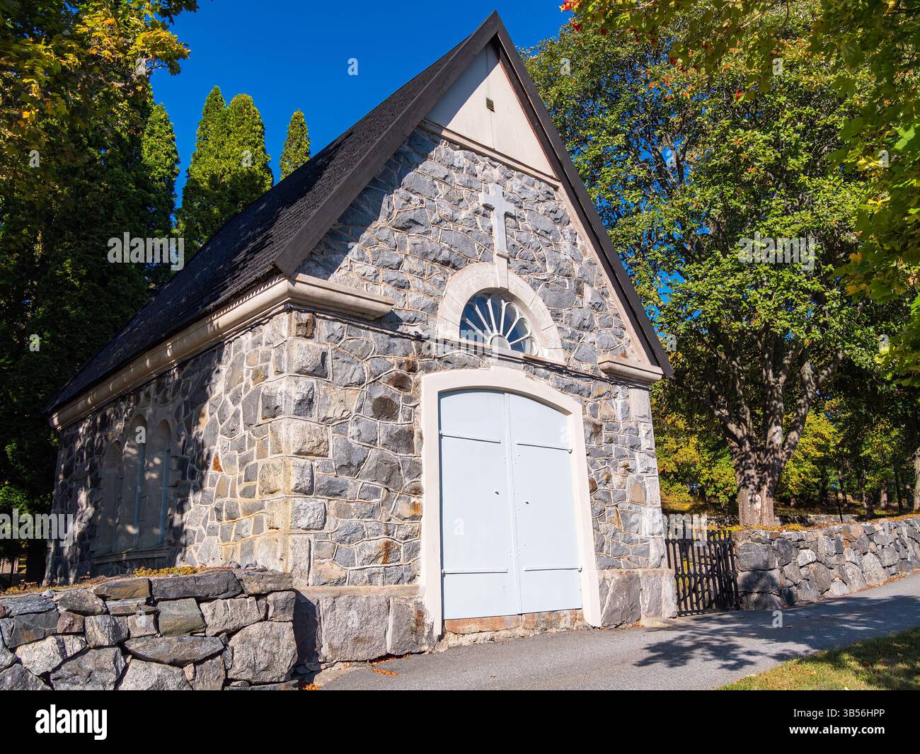 A small stone chapel with a triangular roof and a white door ...