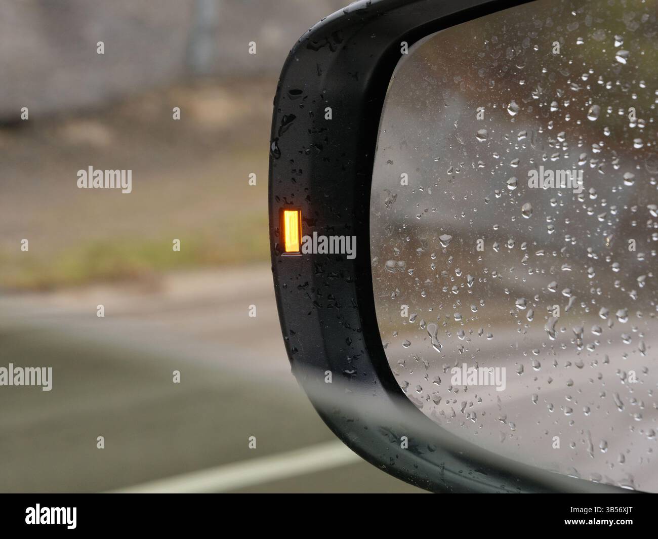 Orange warning light flashing on car side mirror indicating presence of ...