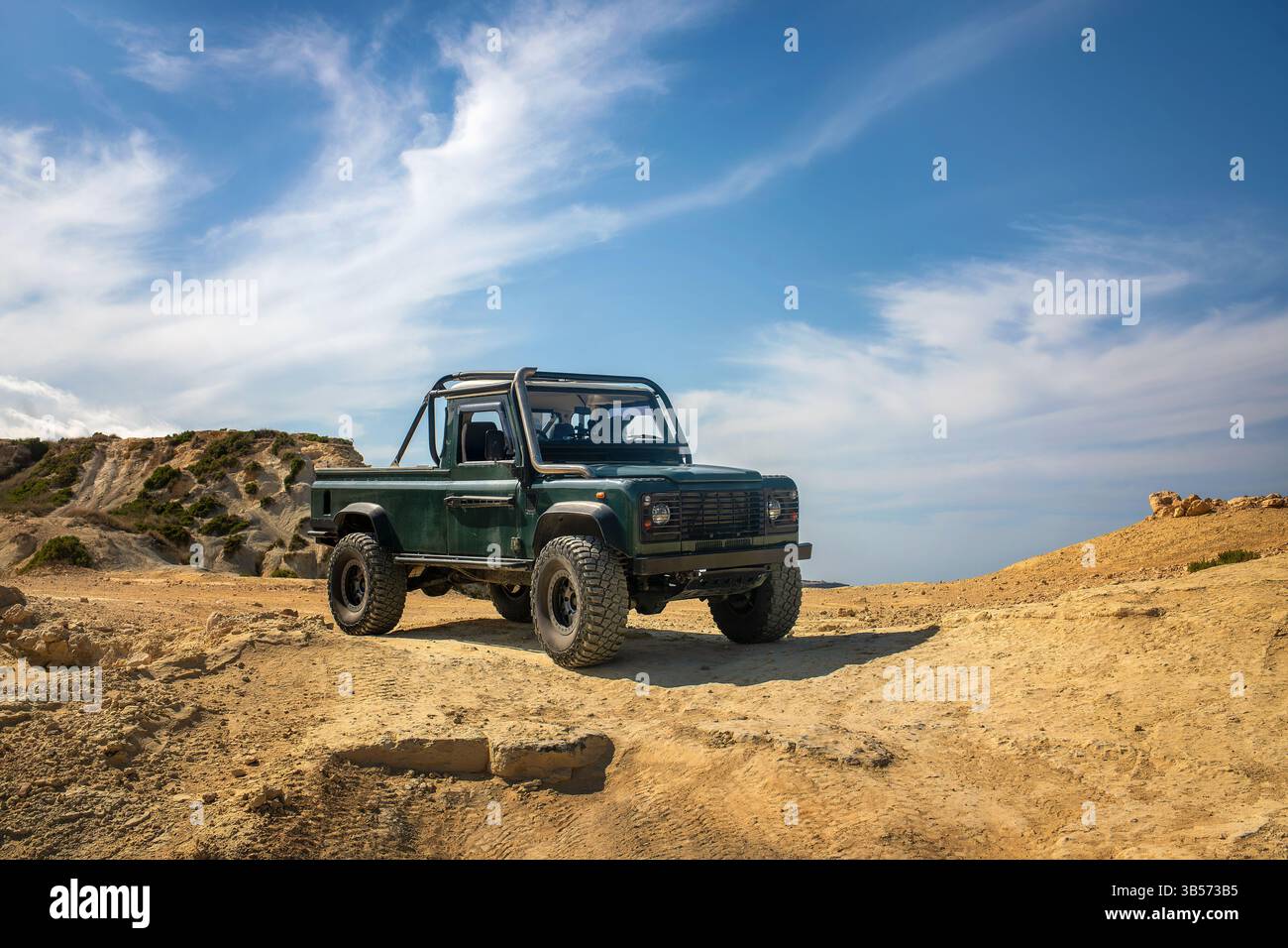 Dust-covered green off-road vehicle with open cargo bed stands on ...