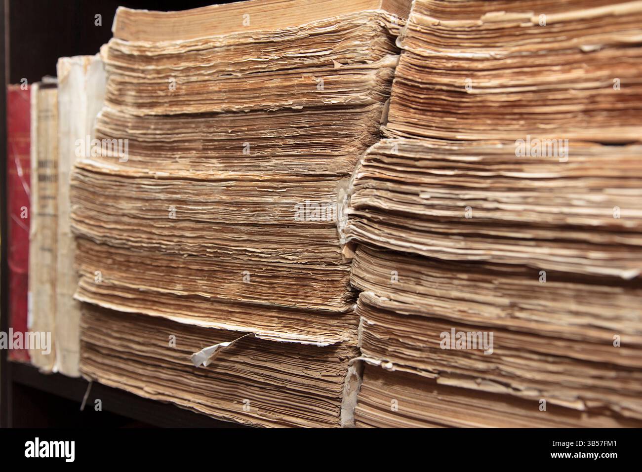 Aged paper documents stacked in rows on a shelf, photographed in close ...