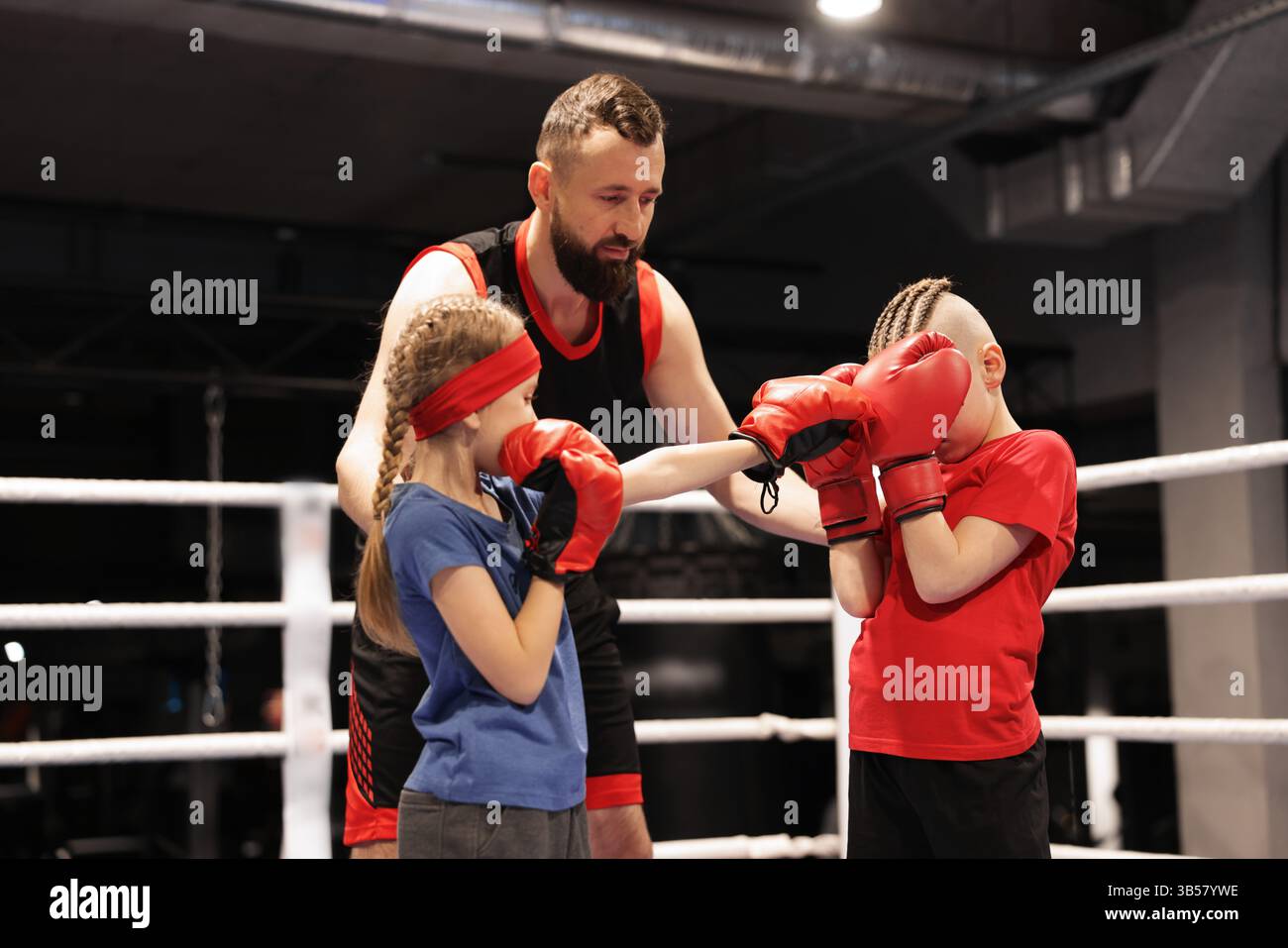 Children practicing fight on boxing ring under their coach supervision ...