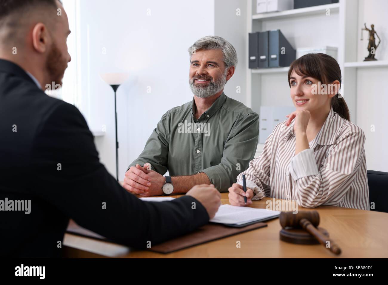 Clients signing notarial paperwork during meeting with lawyer at wooden ...