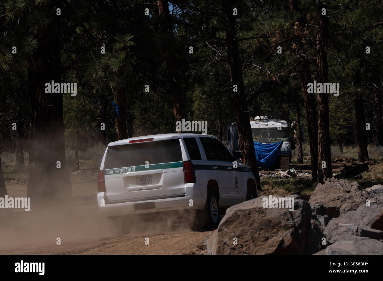 A U.S. Forest Service vehicle drives down a dirt road past newly placed ...