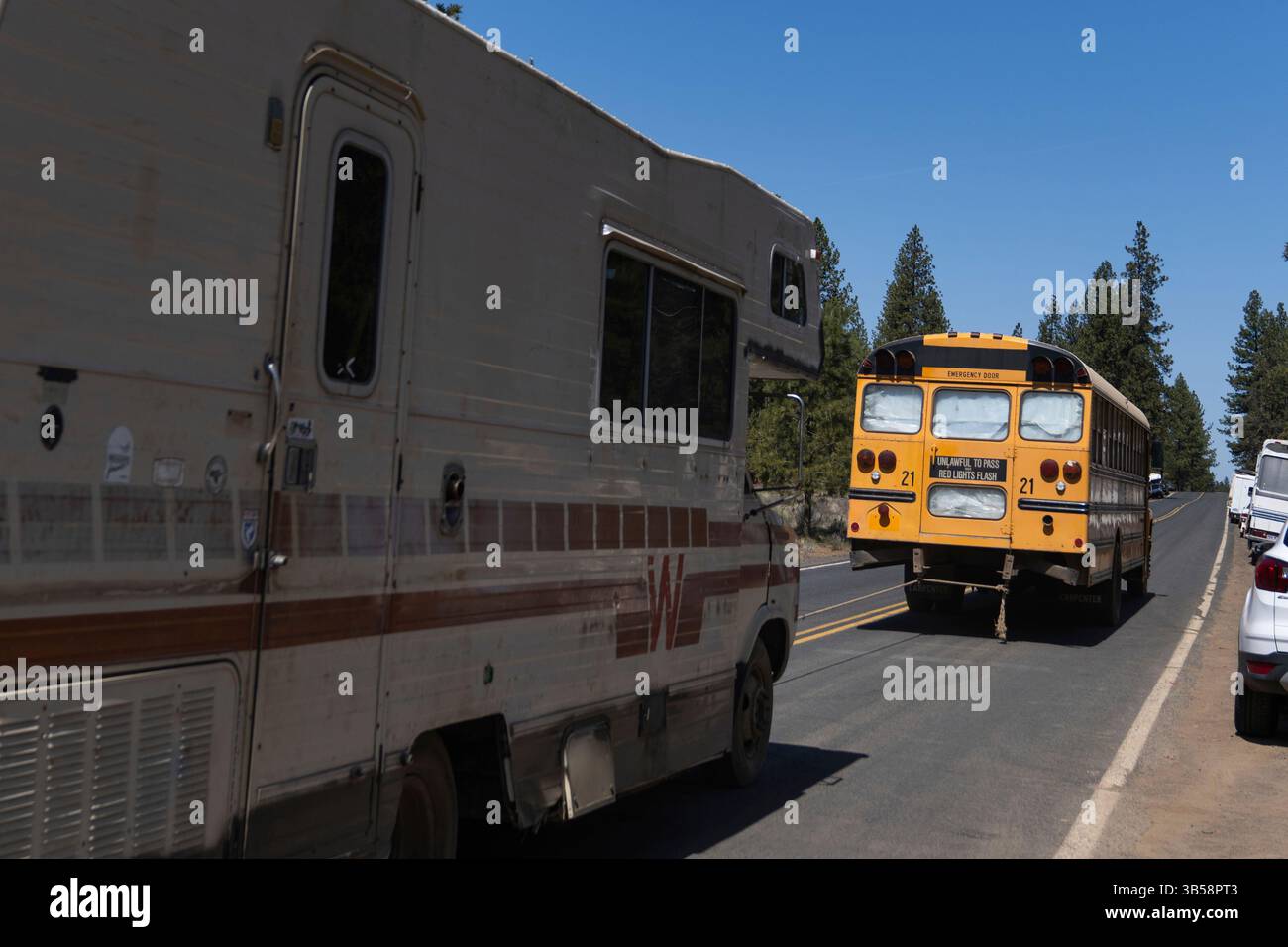 A school bus has a rope tied to the back to tow a trailer out of a ...
