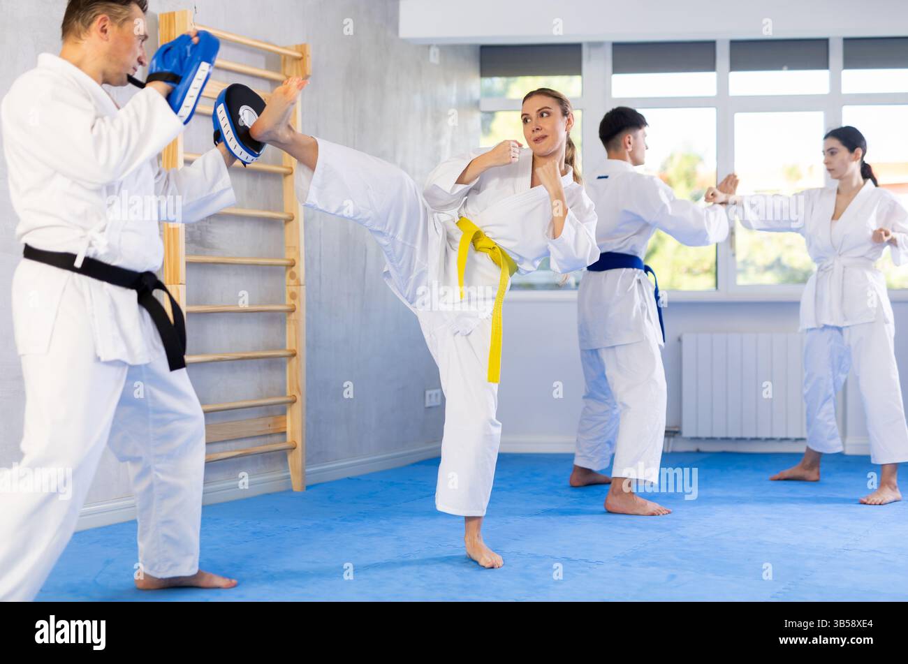 arate trainer helps woman learn how to kick during karate training ...