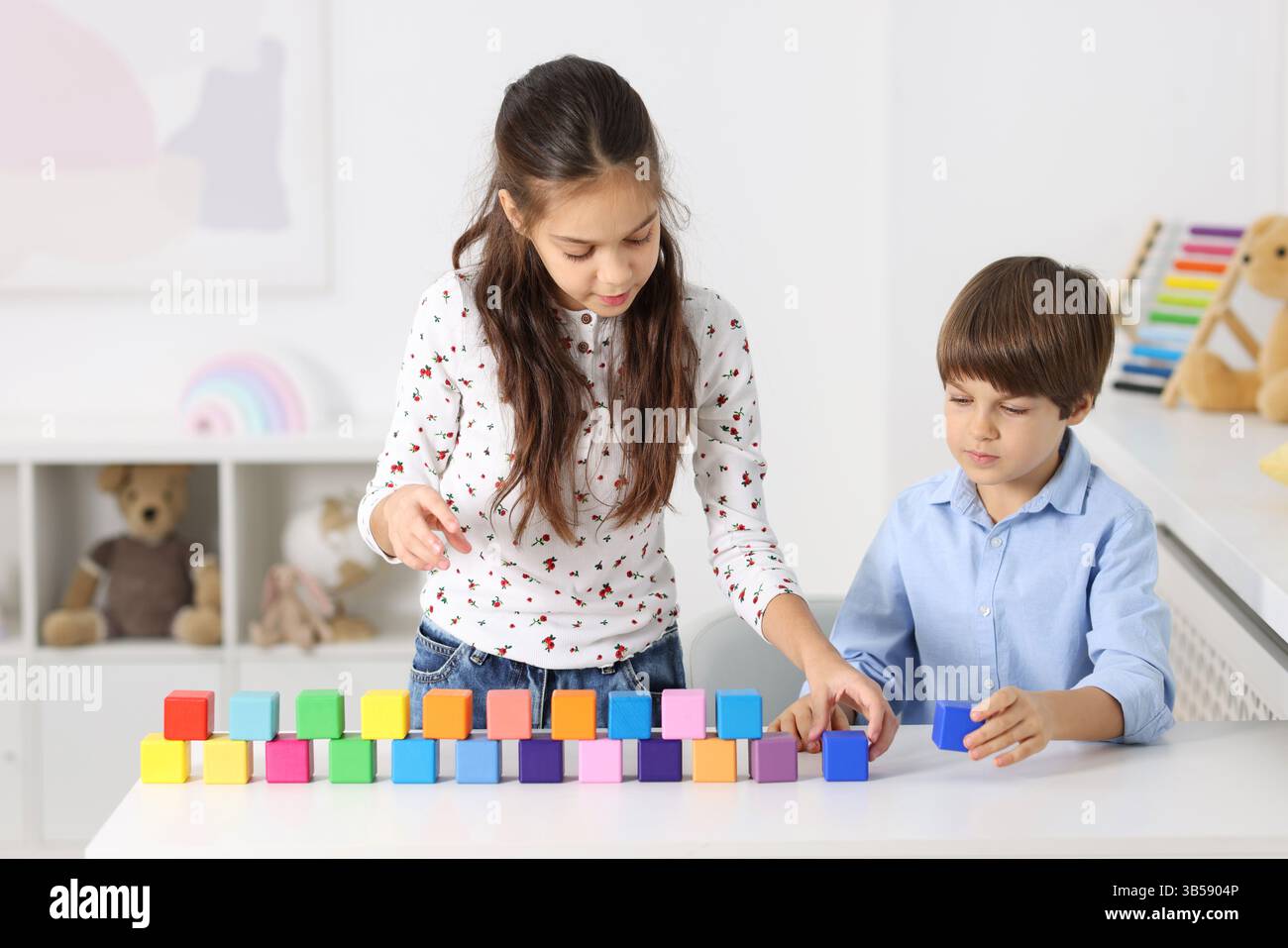 Children playing with colorful cubes at table indoors Stock Photo - Alamy