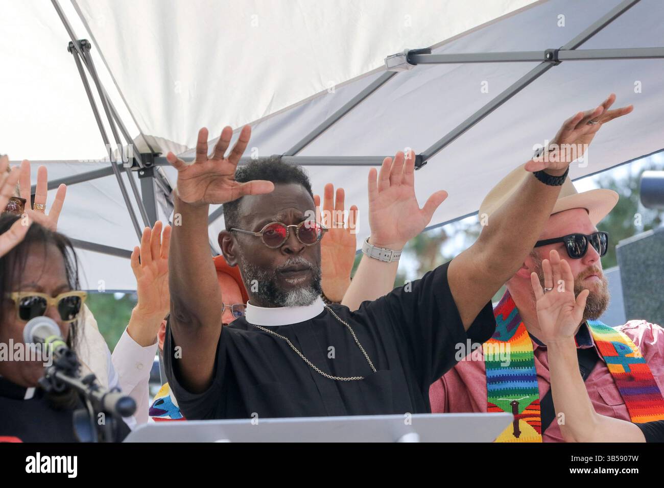 The people on stage raise their hands as Rev. Dr. Cathy Patterson does ...