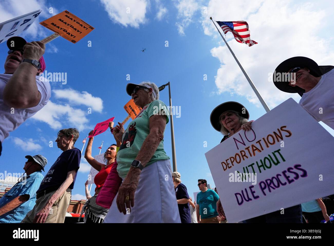 Demonstrators hold signs as they march before a May Day rally outside ...