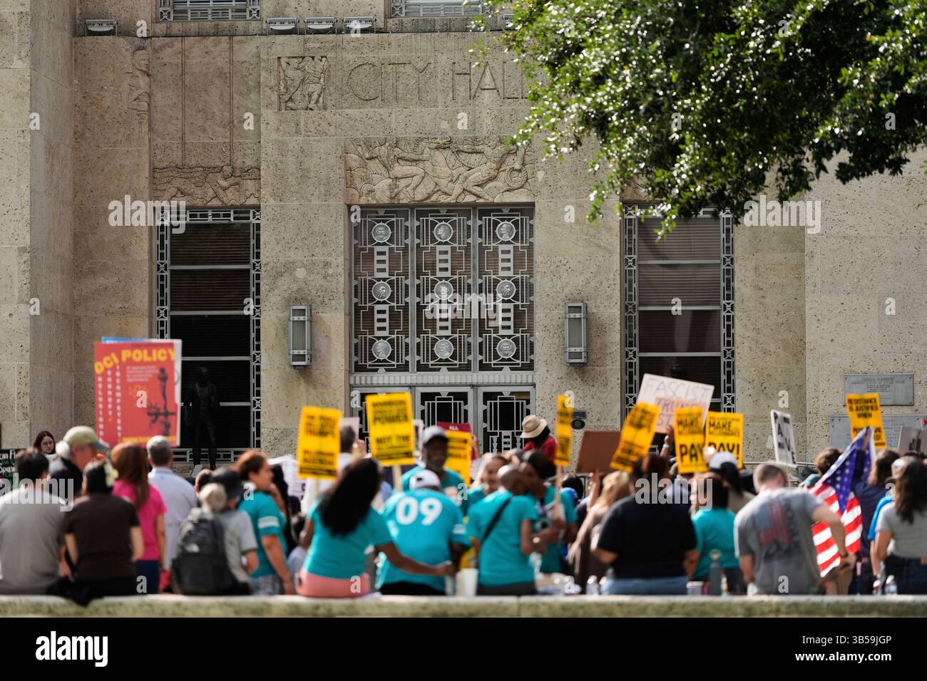 Demonstrators hold signs during a May Day rally outside City Hall on ...