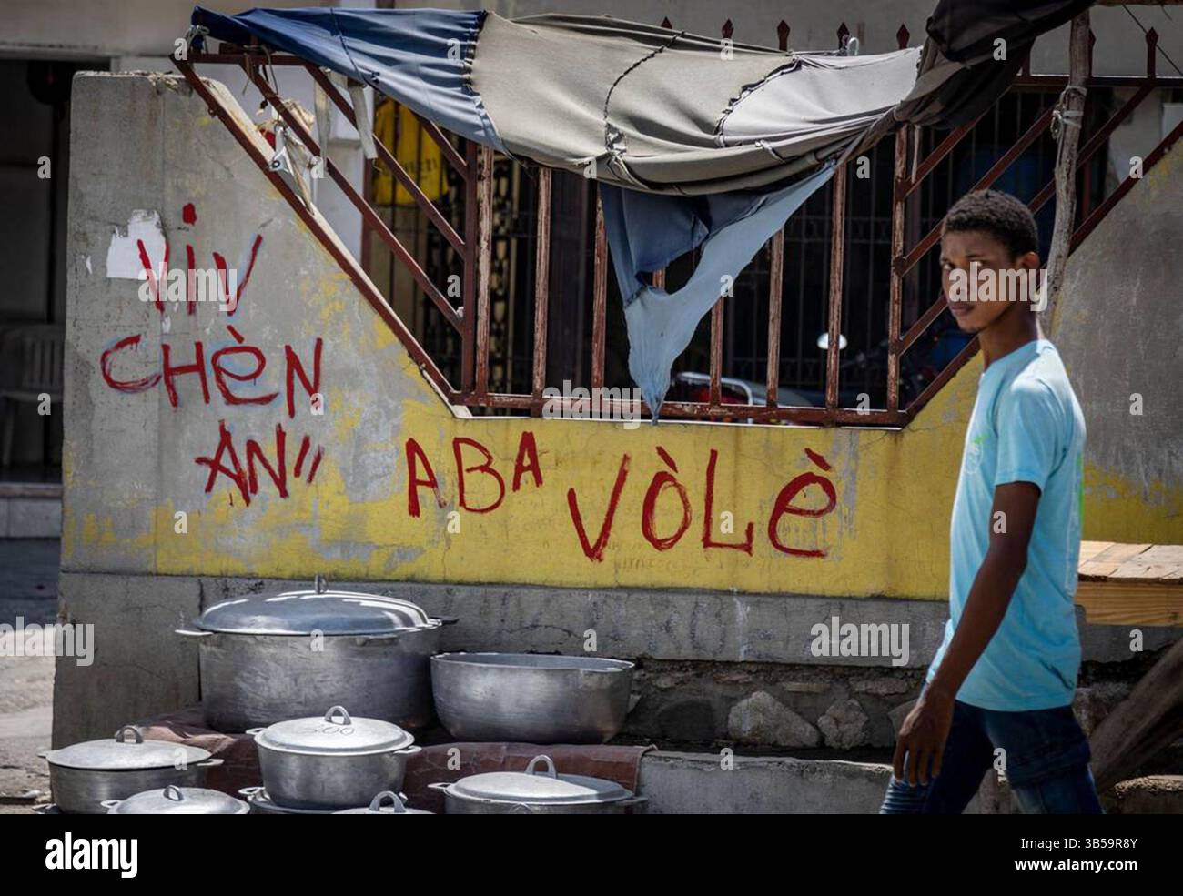 July 7, 2022: A young man walks by gang-related graffiti near a Haiti ...