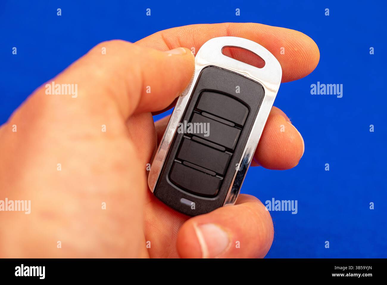 four-button remote control for opening garage doors held in hand on ...