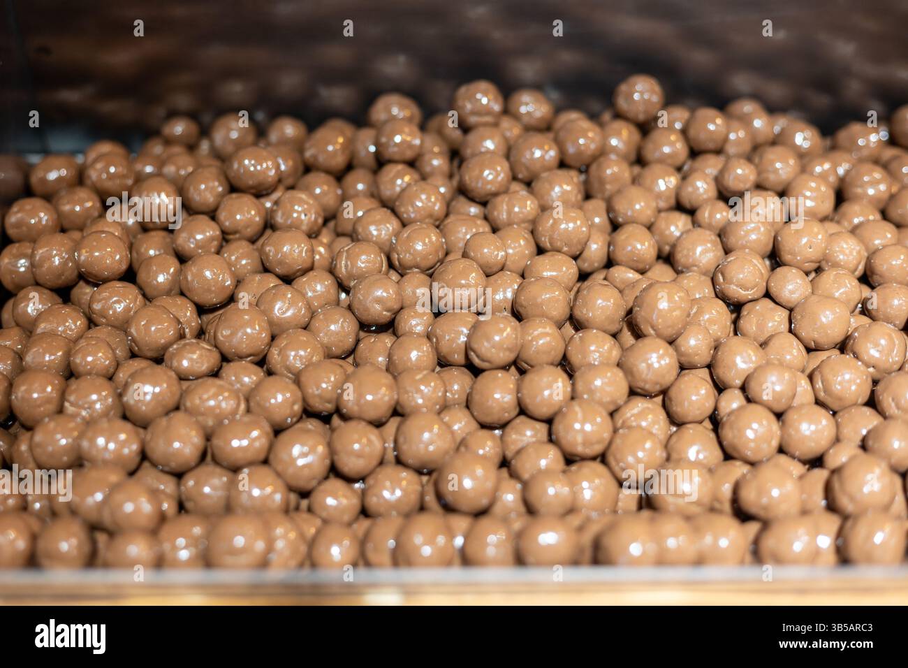 A vibrant display of shiny brown chocolate candies is seen in a factory ...