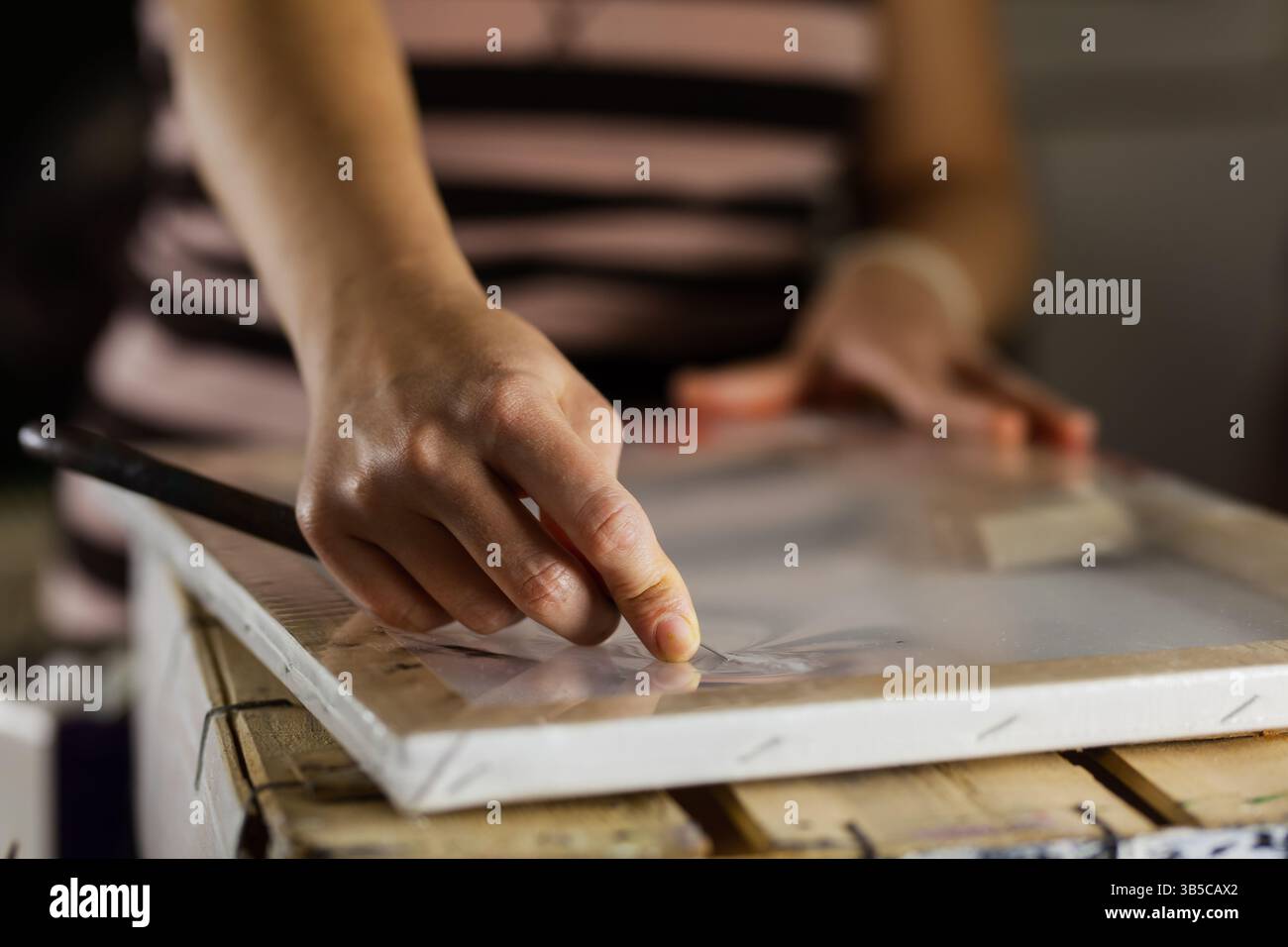 A close-up view of a female artist's hands as she meticulously traces ...