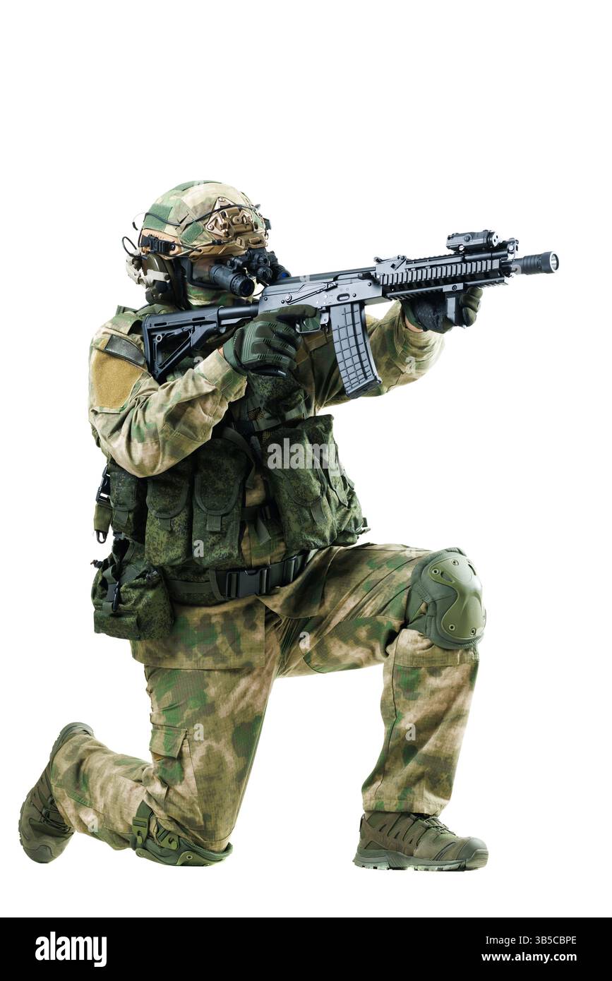 A soldier wearing camouflage uniform and tactical equipment kneels ...