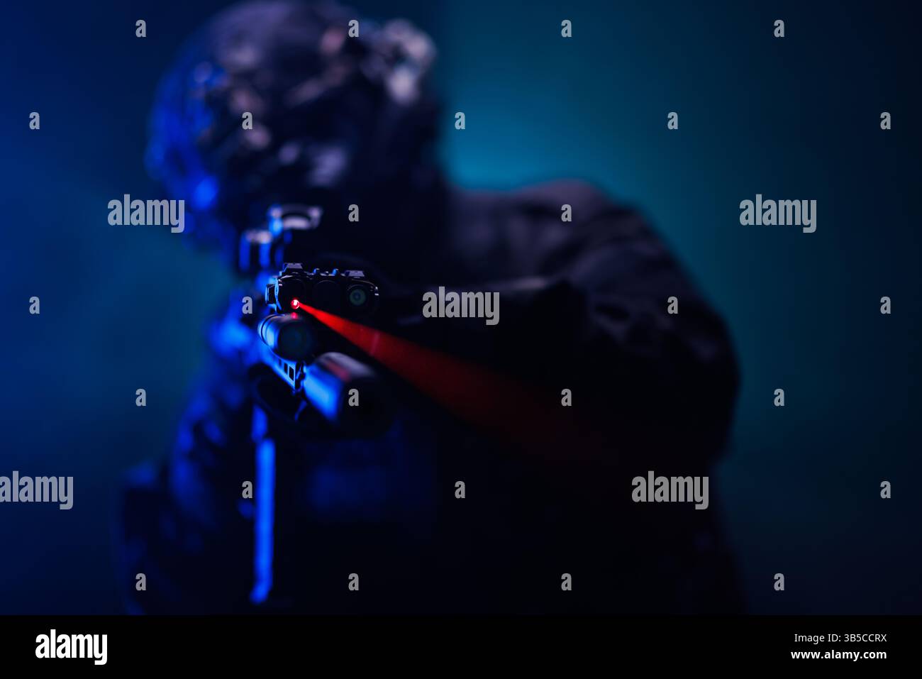 A figure wearing tactical gear, aiming a weapon equipped with a laser ...