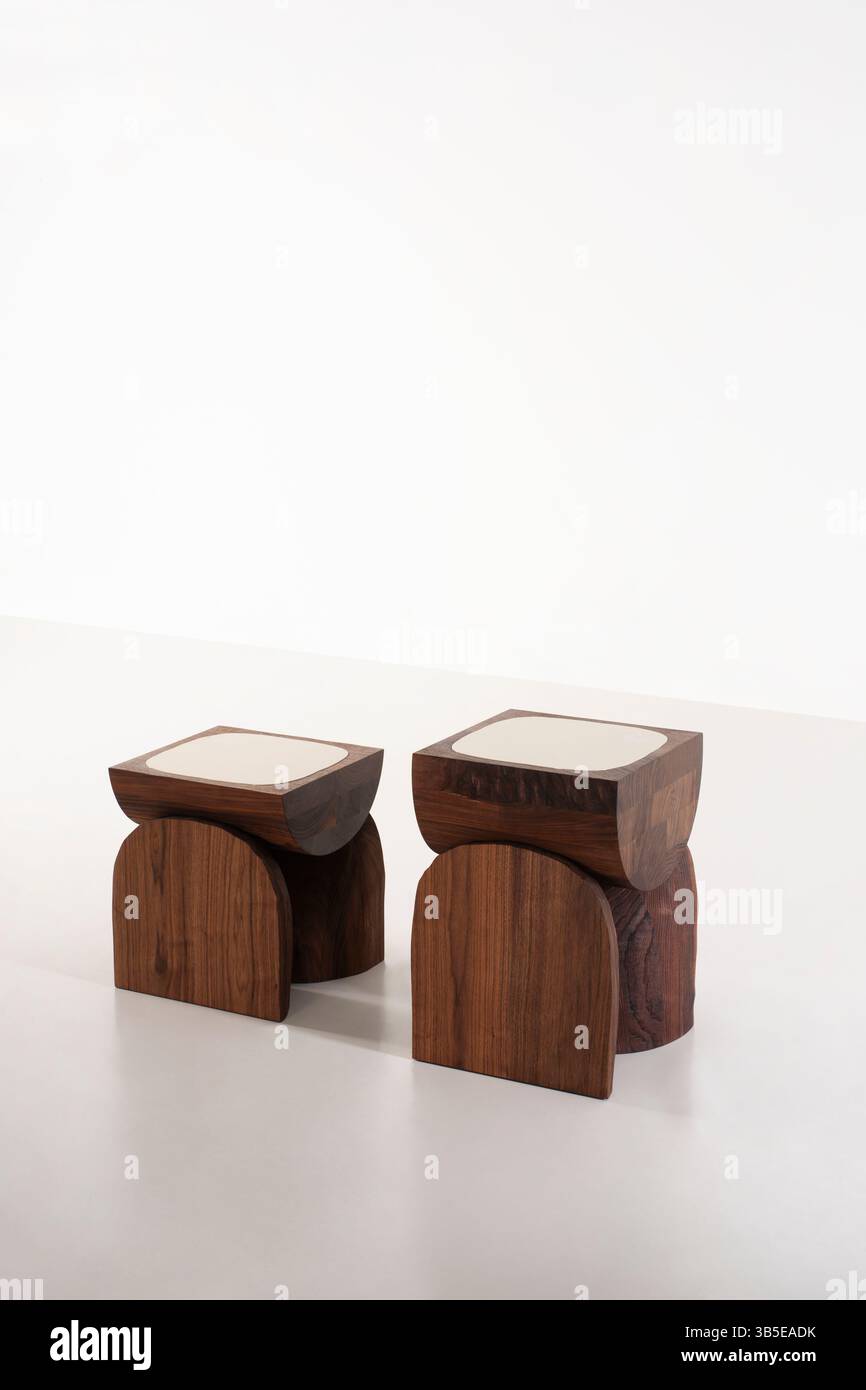 two geometrically shaped wooden stools with white inserts rest on a ...