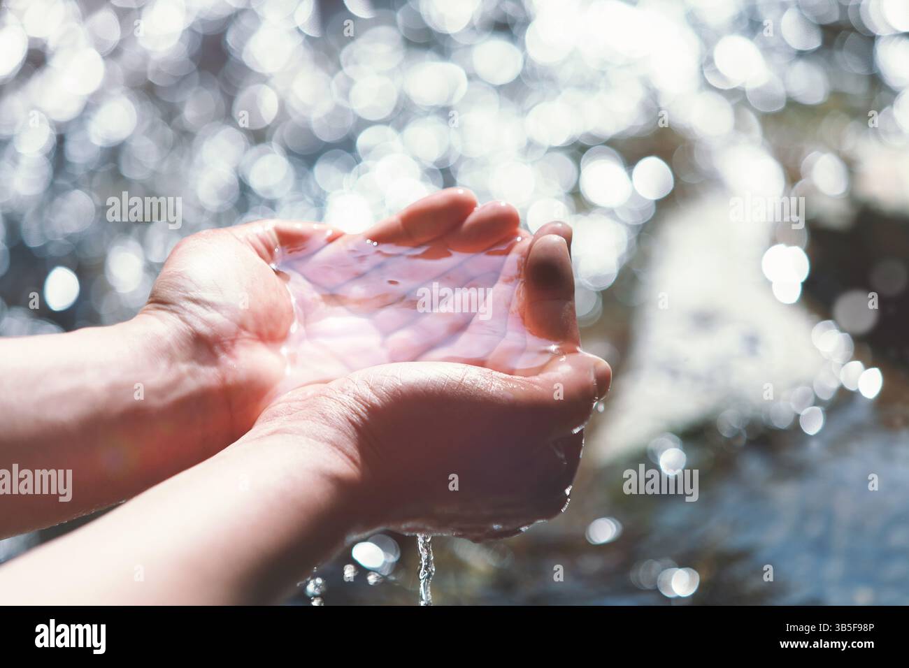 Precious spring water in your hand, clear, transparent and clean water ...