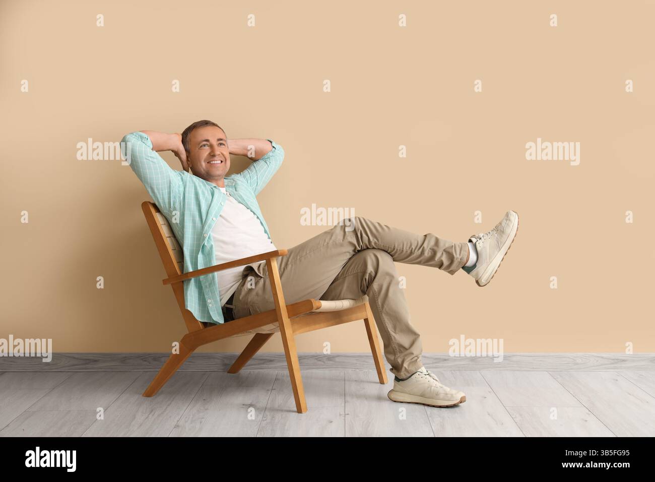 Old man resting in armchair near beige wall Stock Photo - Alamy