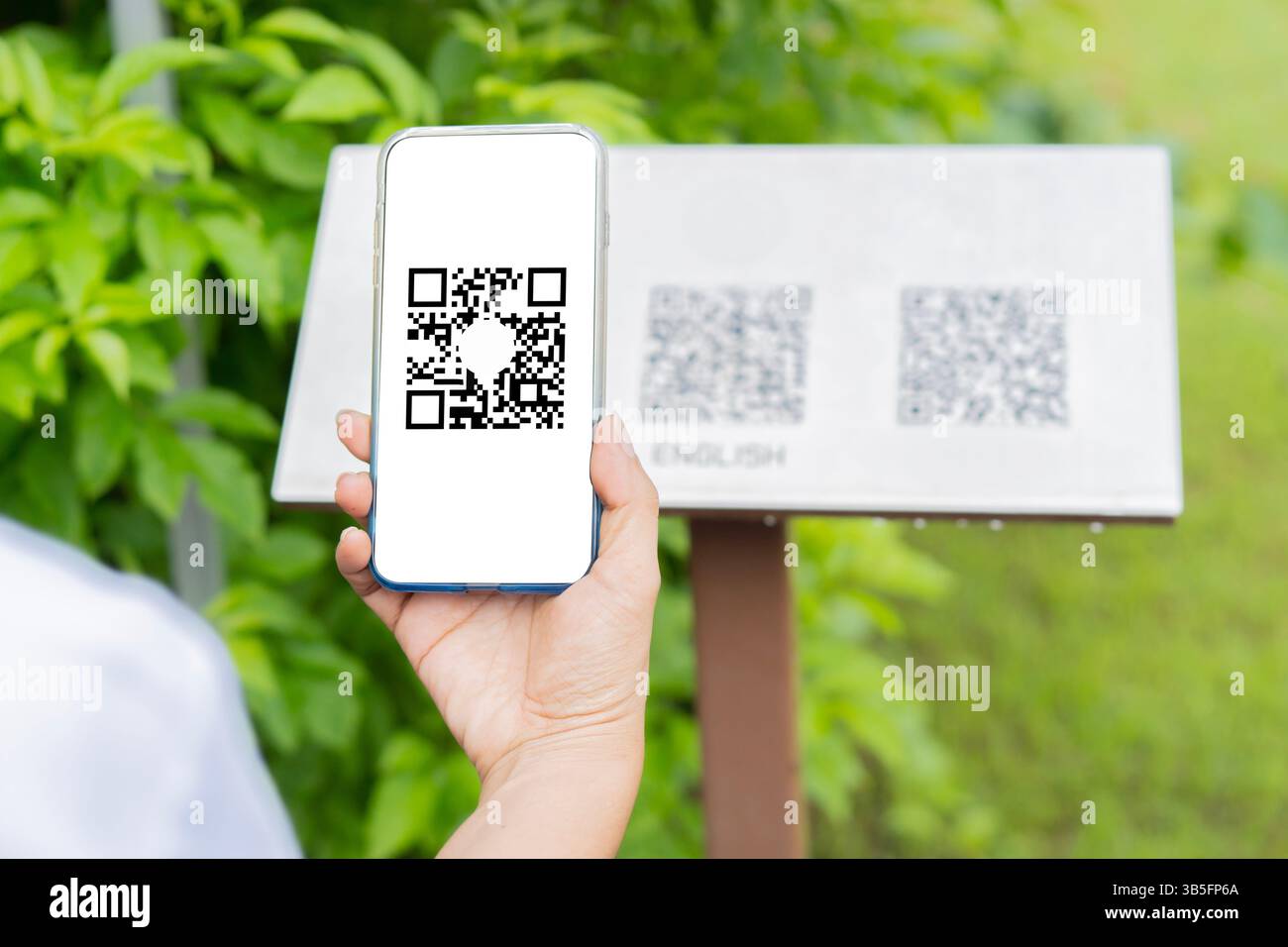 Hand holding smartphone with scanning QR code smart guide screen with guide for visitors sign on ...