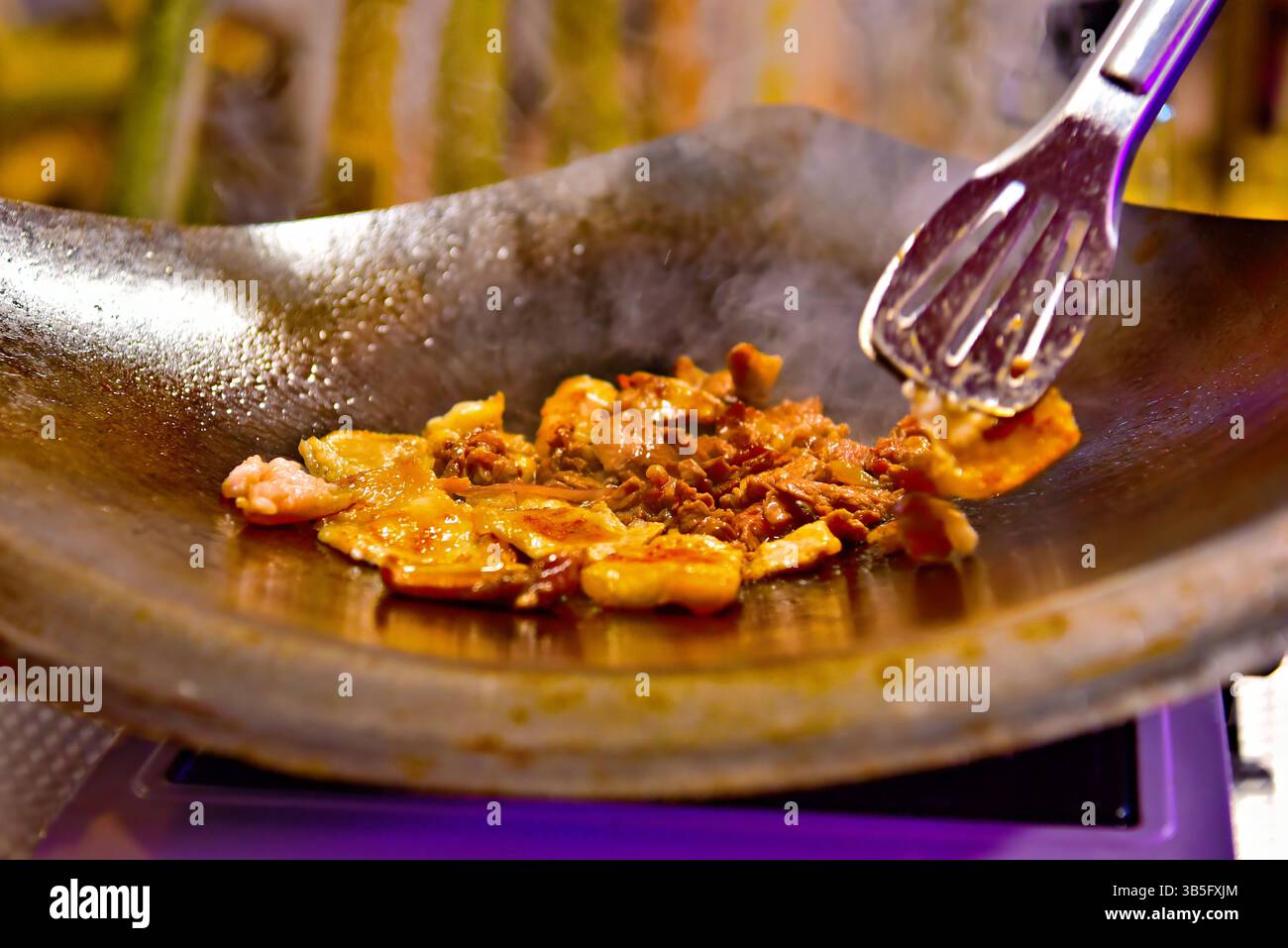 Stir fried beef served table side. A Chinese wok cut into 4 quadrants ...