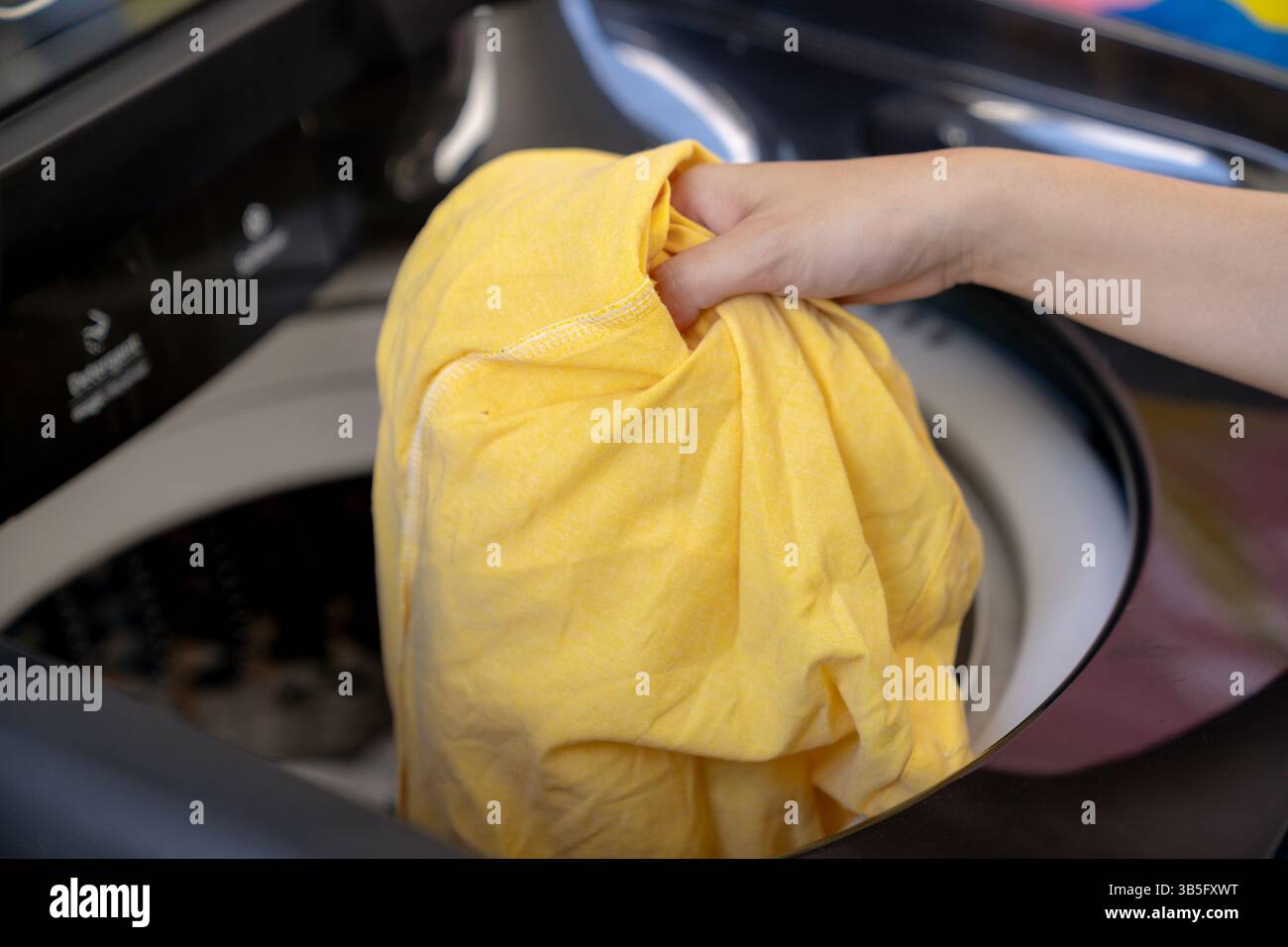 Delicate hands carefully loading laundry into a front-loading washing ...