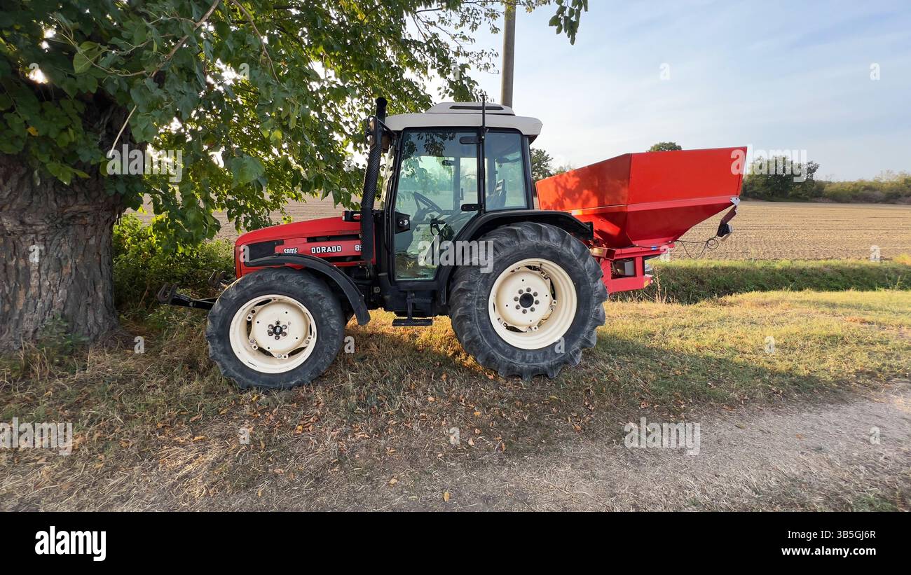 Agricultural tractor with red fertilizer spreader standing in rural ...