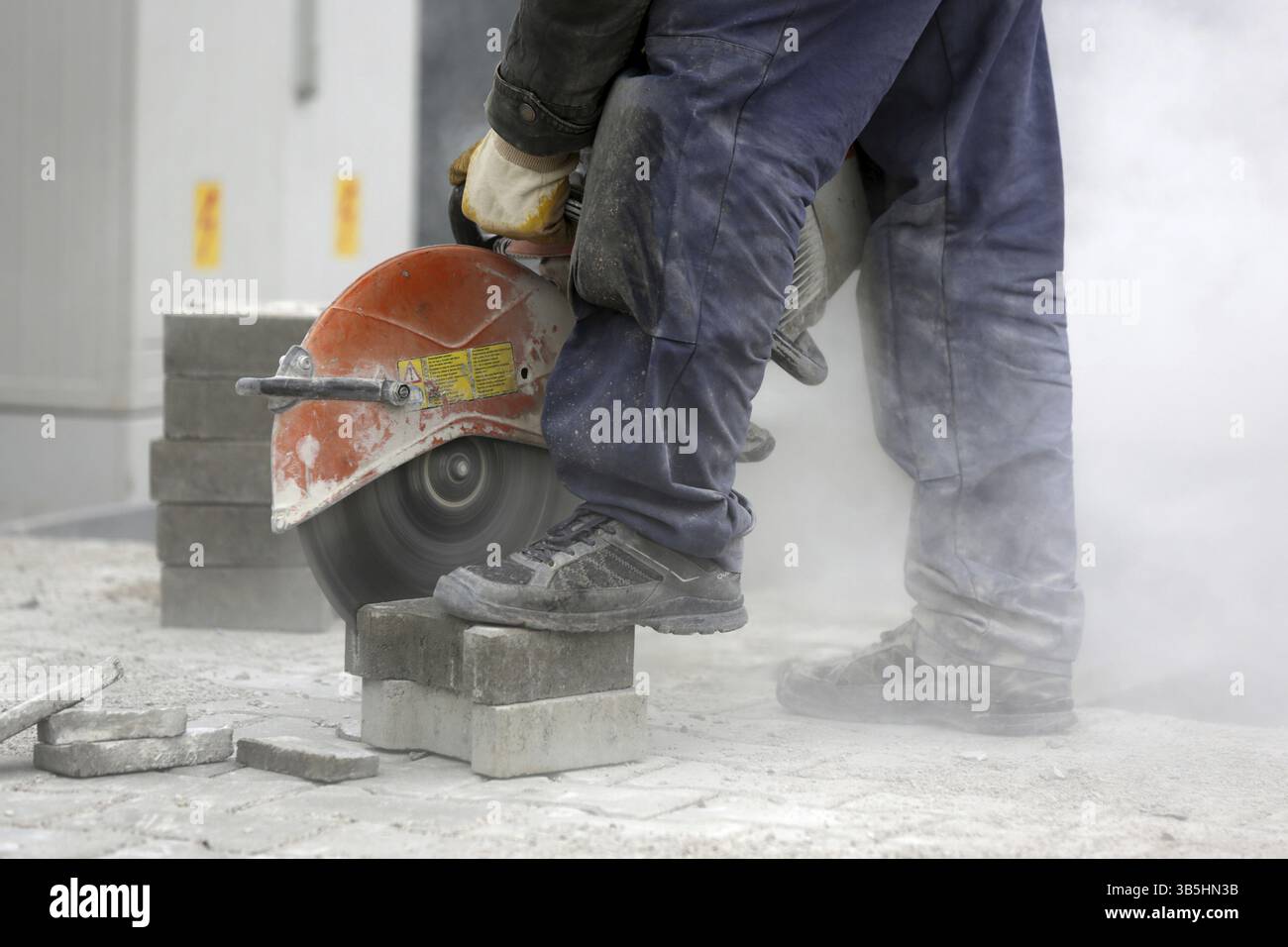 Worker uses a stone cutter to cut the brick pavers. Cutting concrete ...