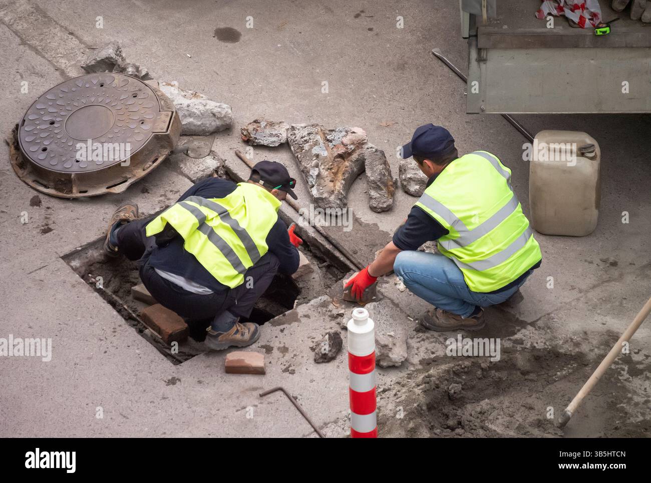 Utility workers repairing underground manhole, performing urban road ...