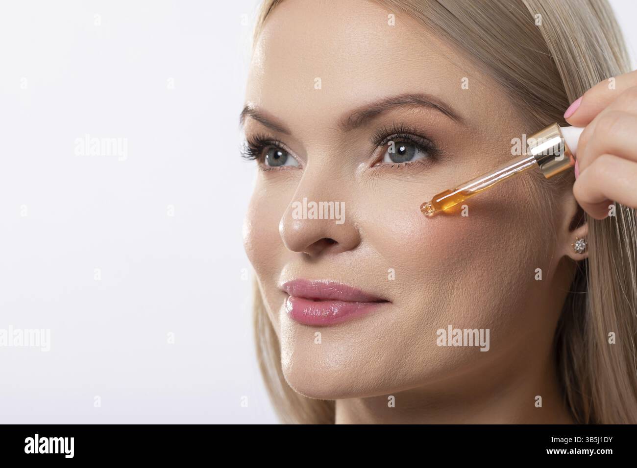 A woman gently applies a brightening serum to her face, promoting ...