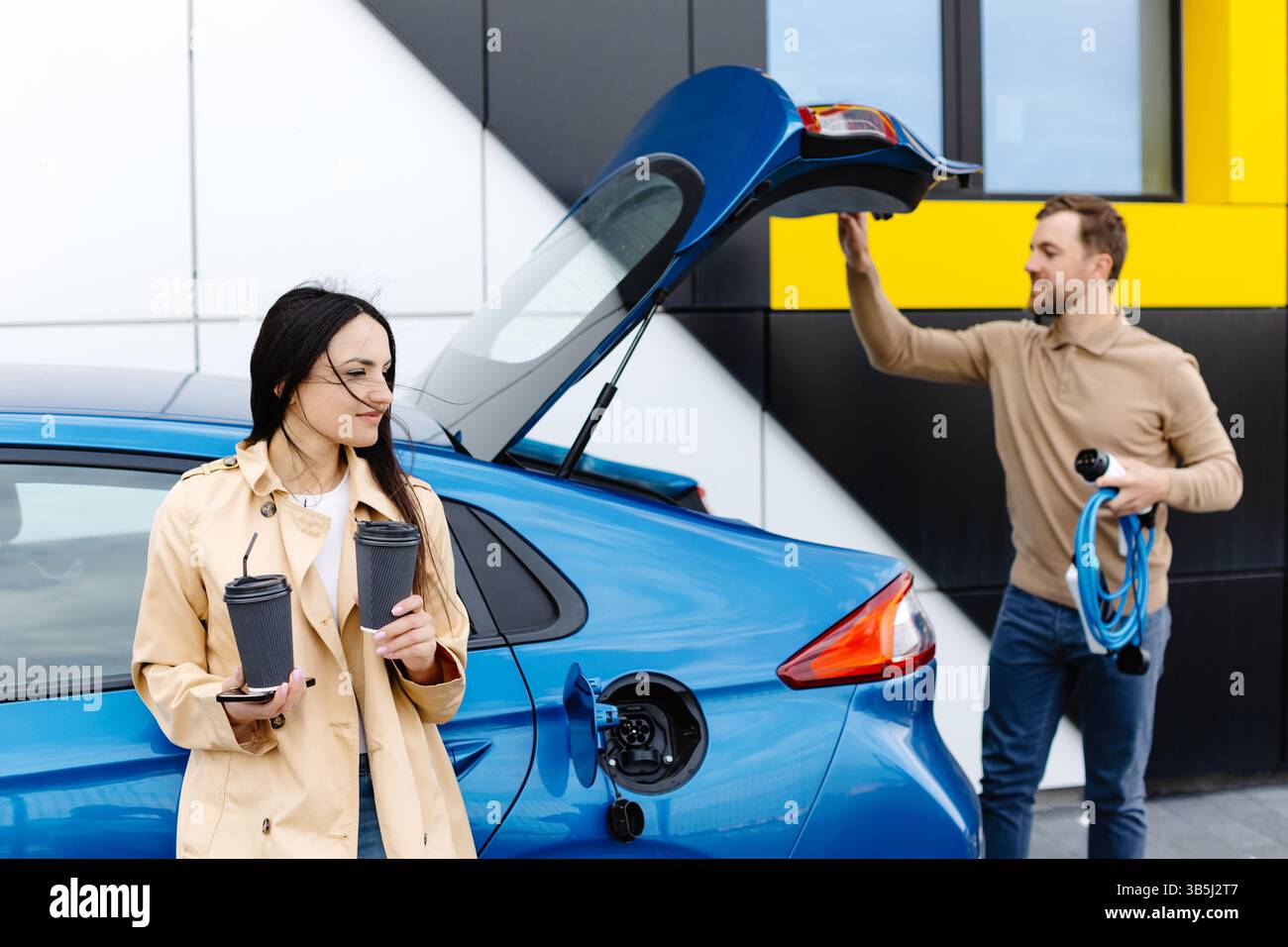 Young couple man and woman traveling by electric car having stop at ...